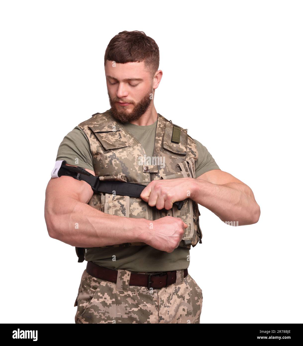 Soldier in military uniform applying medical tourniquet on arm against ...