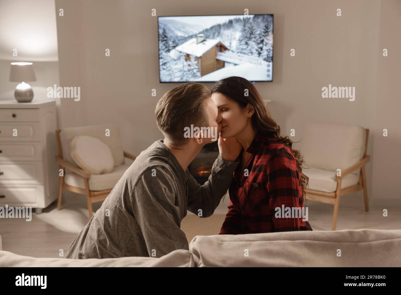 Lovely couple kissing near fireplace at home Stock Photo - Alamy