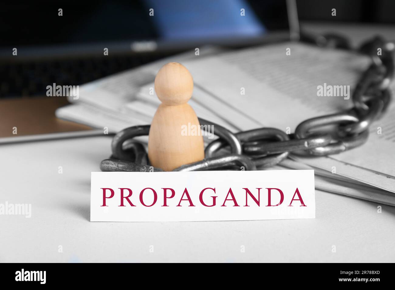Propaganda concept. Chained wooden figure and newspapers on table Stock ...