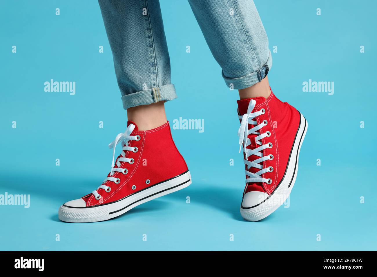 Woman in stylish gumshoes on light blue background, closeup Stock Photo ...