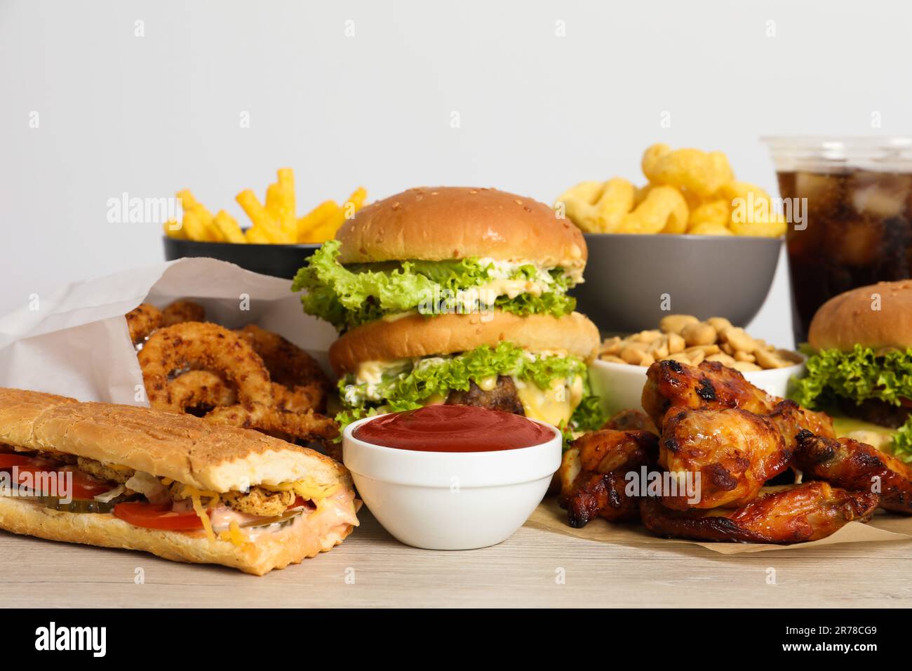 French fries, burgers and other fast food on wooden table against white ...
