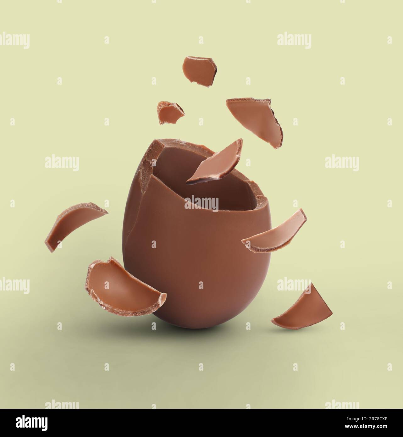 Exploded milk chocolate egg on beige background Stock Photo - Alamy