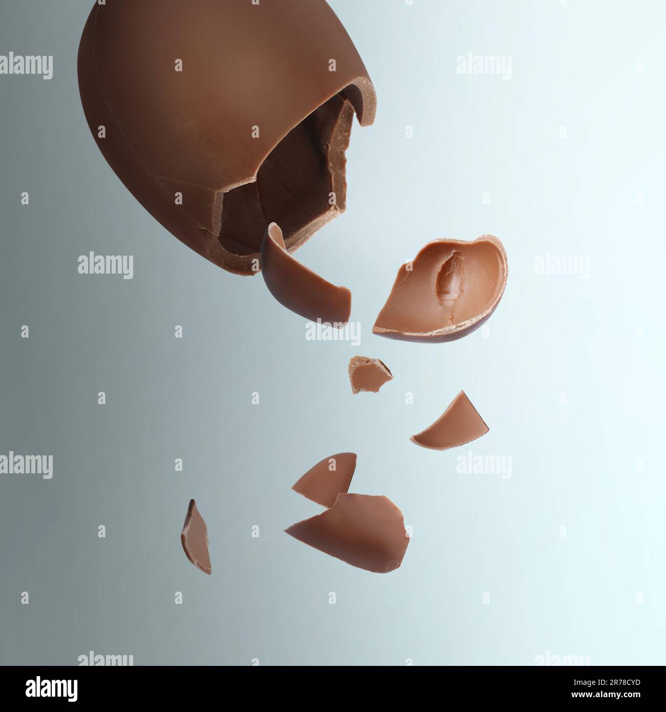 Exploded milk chocolate egg on color background Stock Photo - Alamy