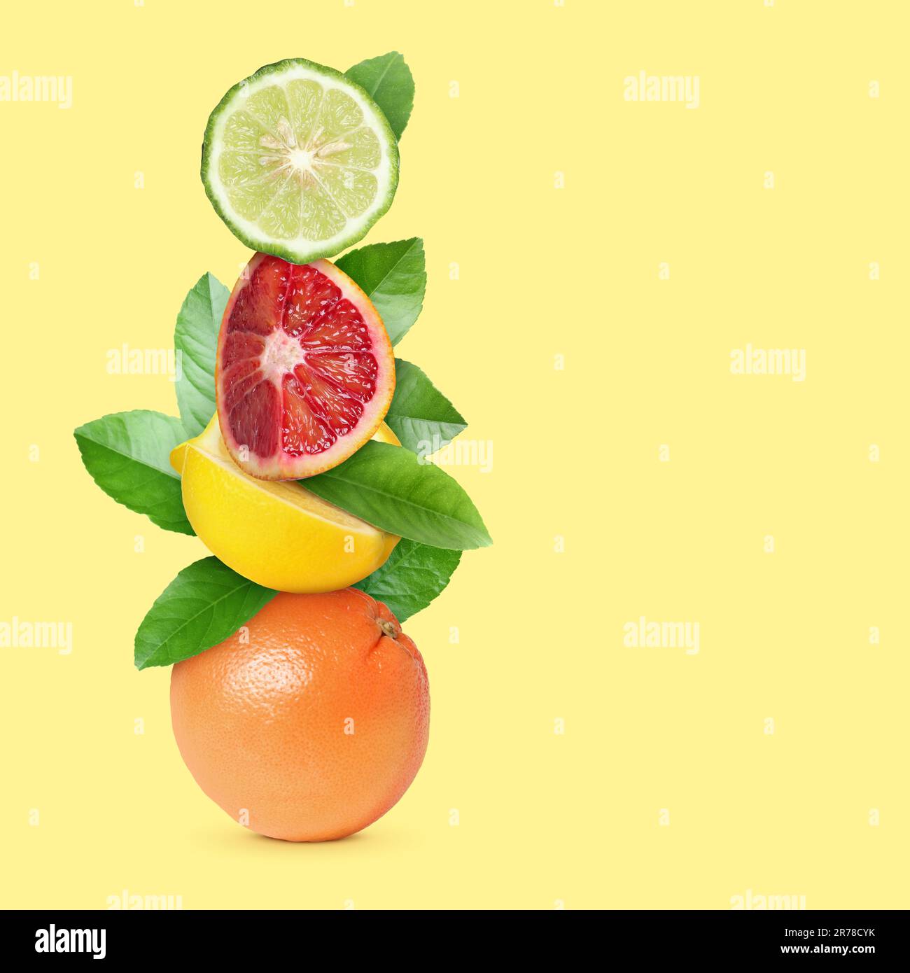 Stack of different fresh citrus fruits with green leaves on pale light ...