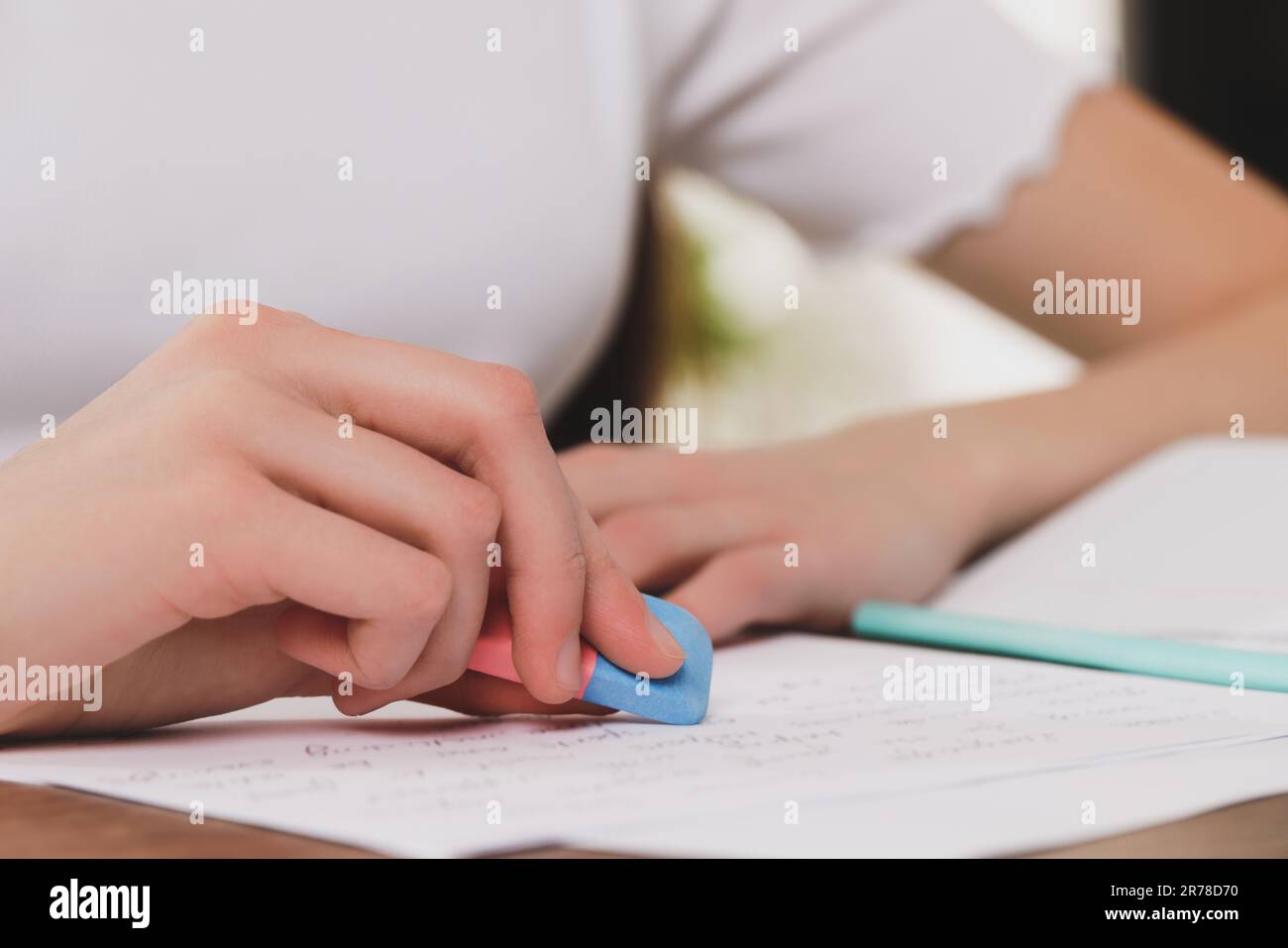Girl erasing mistake in her notebook at wooden desk, closeup Stock ...
