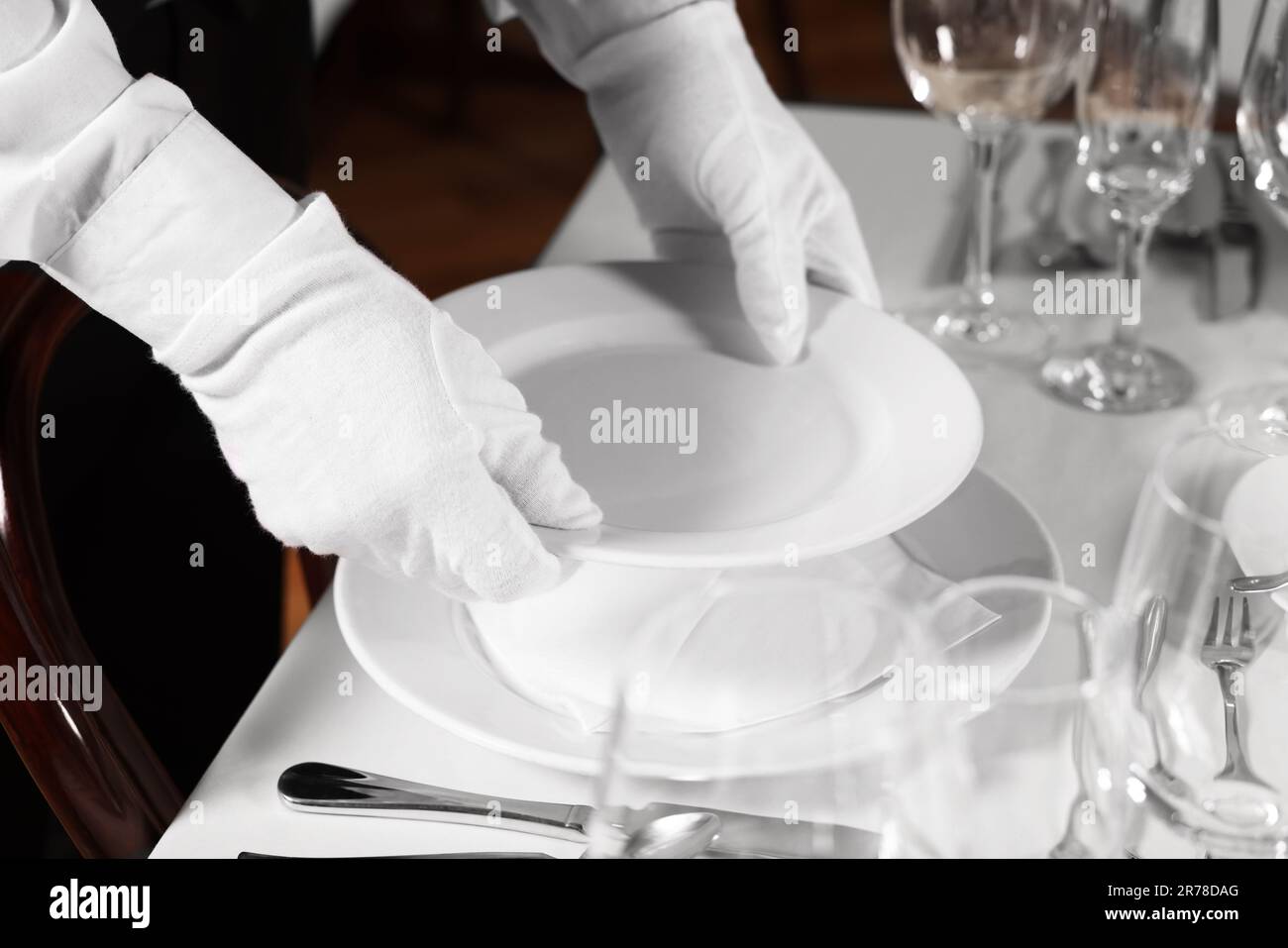 Woman setting table in restaurant, closeup. Professional butler courses ...