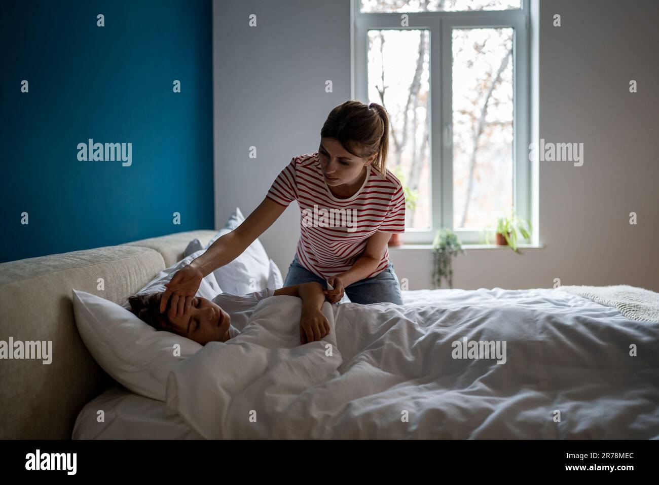 Caring mother checking temperature of sick daughter, taking care of ...