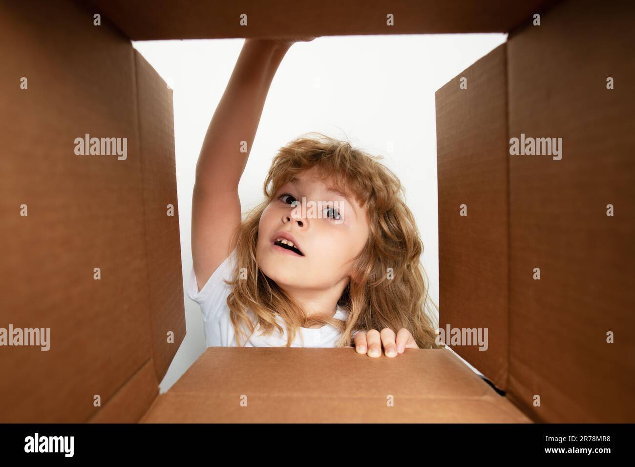 Cheerful cute child opening a present. Cardboard boxes, parcels ...