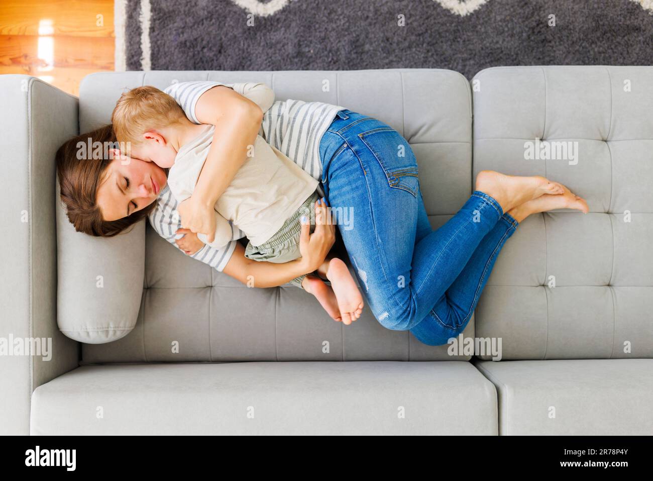 Mother embraces her cute little son while laying together on the couch Stock Photo - Alamy