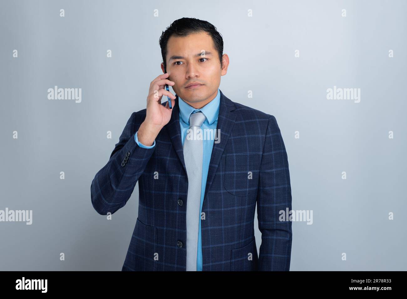 Latino Businessman Listens on Worried Phone in Business Suit with Gray ...