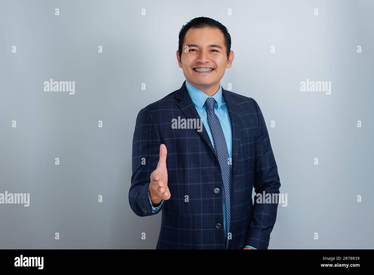 Young businessman, Hispanic ethnicity smiles in braces, waves with his ...