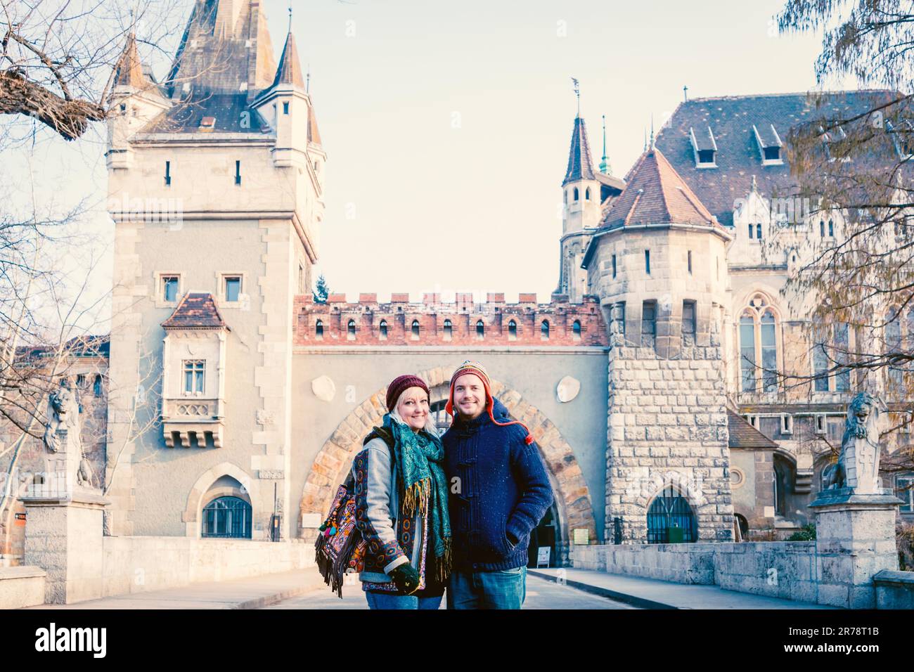 An attractive young couple stands in front of a majestic castle in a ...