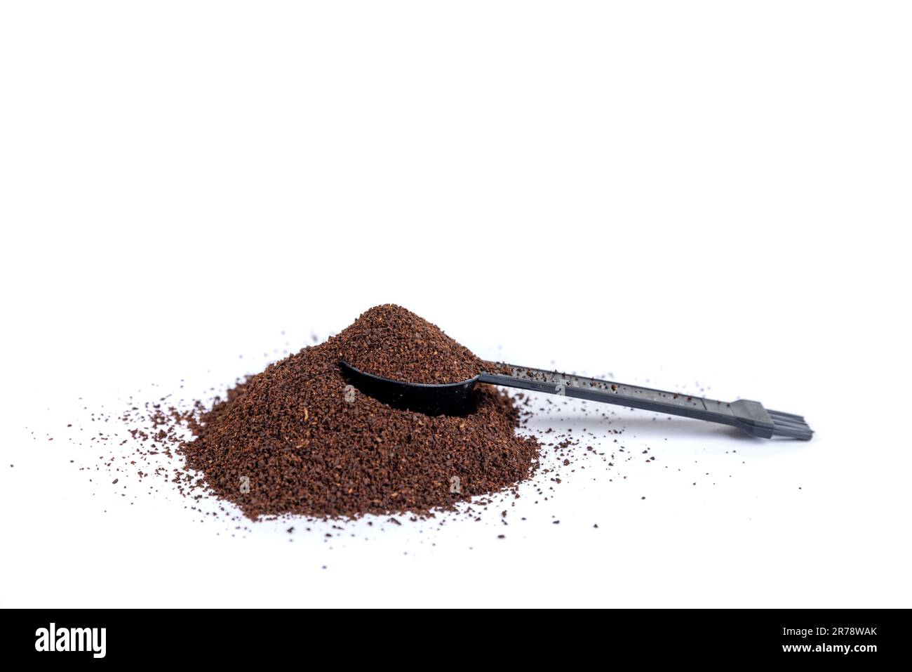 Serving measuring scoop full of coffee grounds in a hill of coffee ...