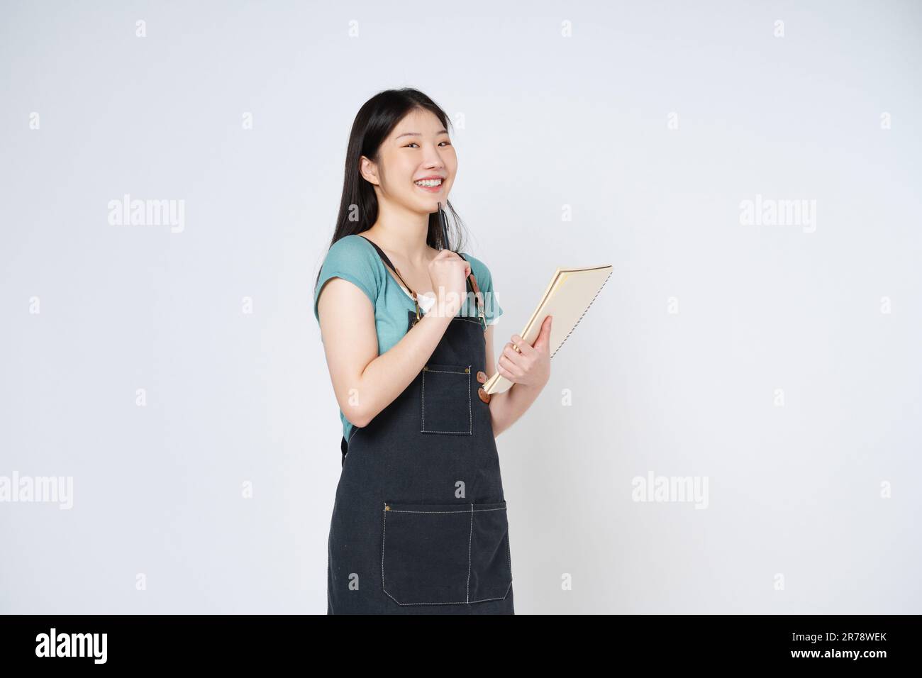 Young woman wearing kitchen apron holding notepad recipe cooking book ...