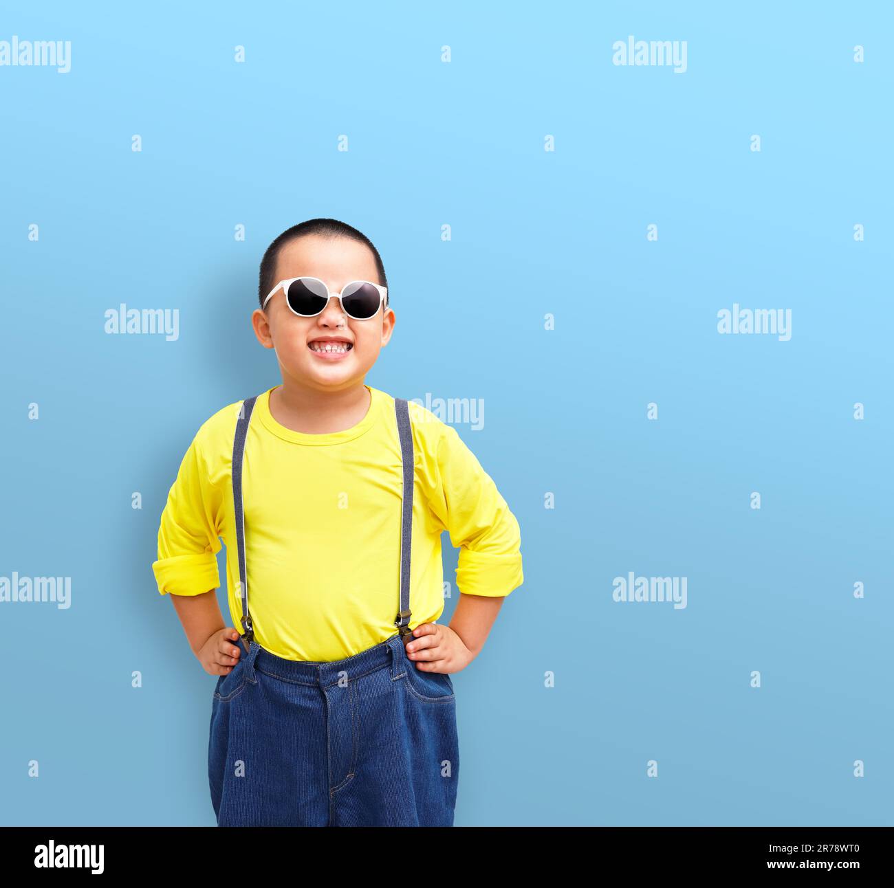 A little boy is hip-akimbo posting and wearing big sunglasses. Isolated ...