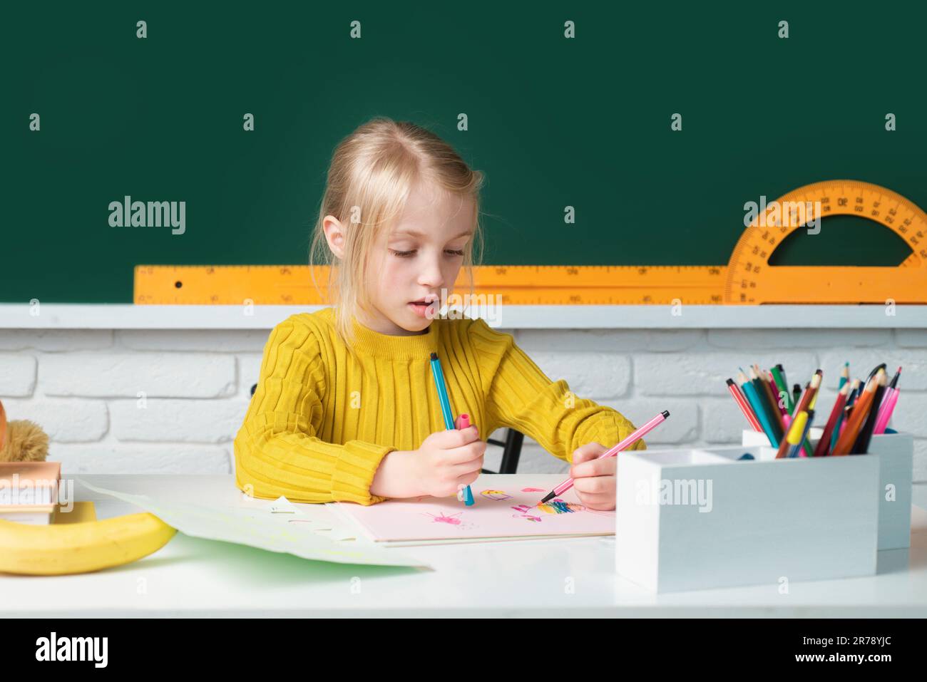 Back to school. Cute pupil girl drawing at the desk. Genius child ...