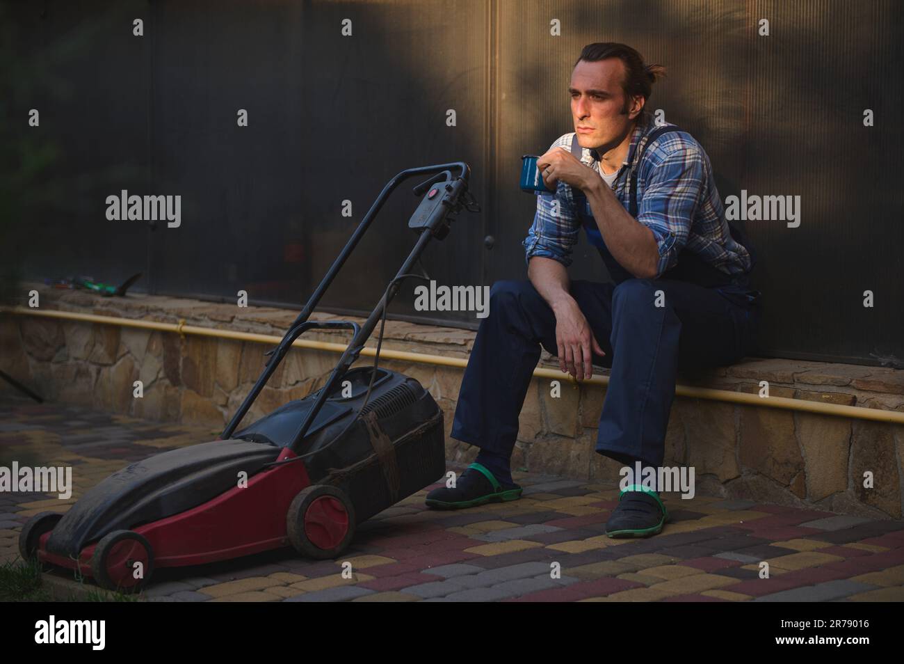 Sunset sun rays fall on face of a gardener man, landscaper with lawn ...