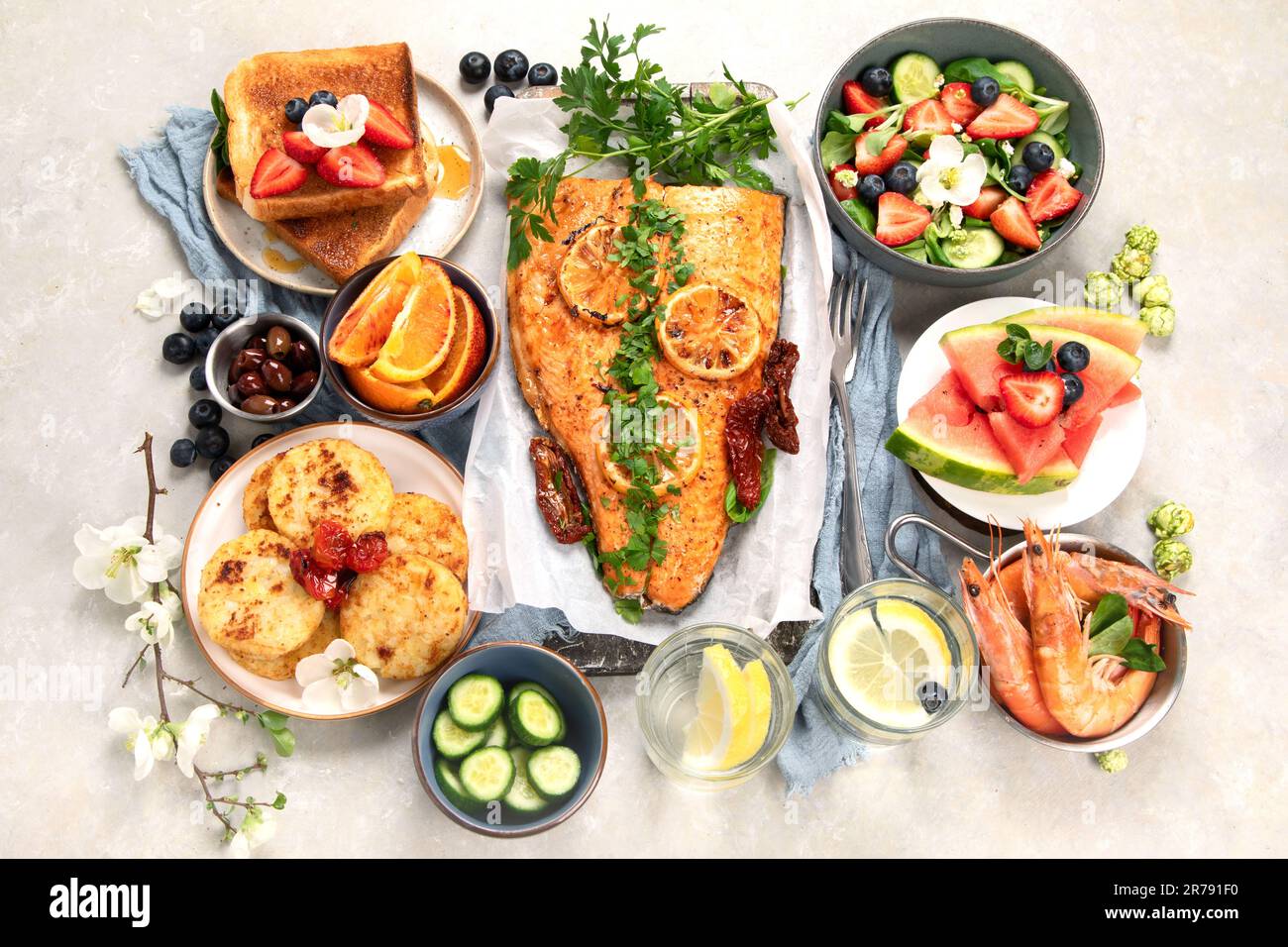 Dinner table with shrimp, fish, salads and different snacks on a white ...