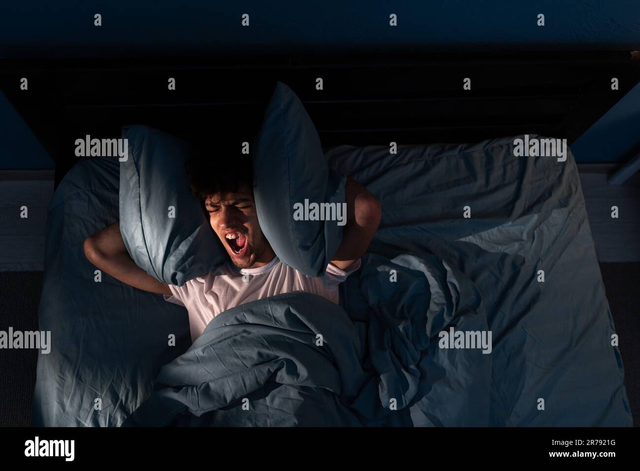 Attractive depressed anxious devastated guy lying on bed shouting ...