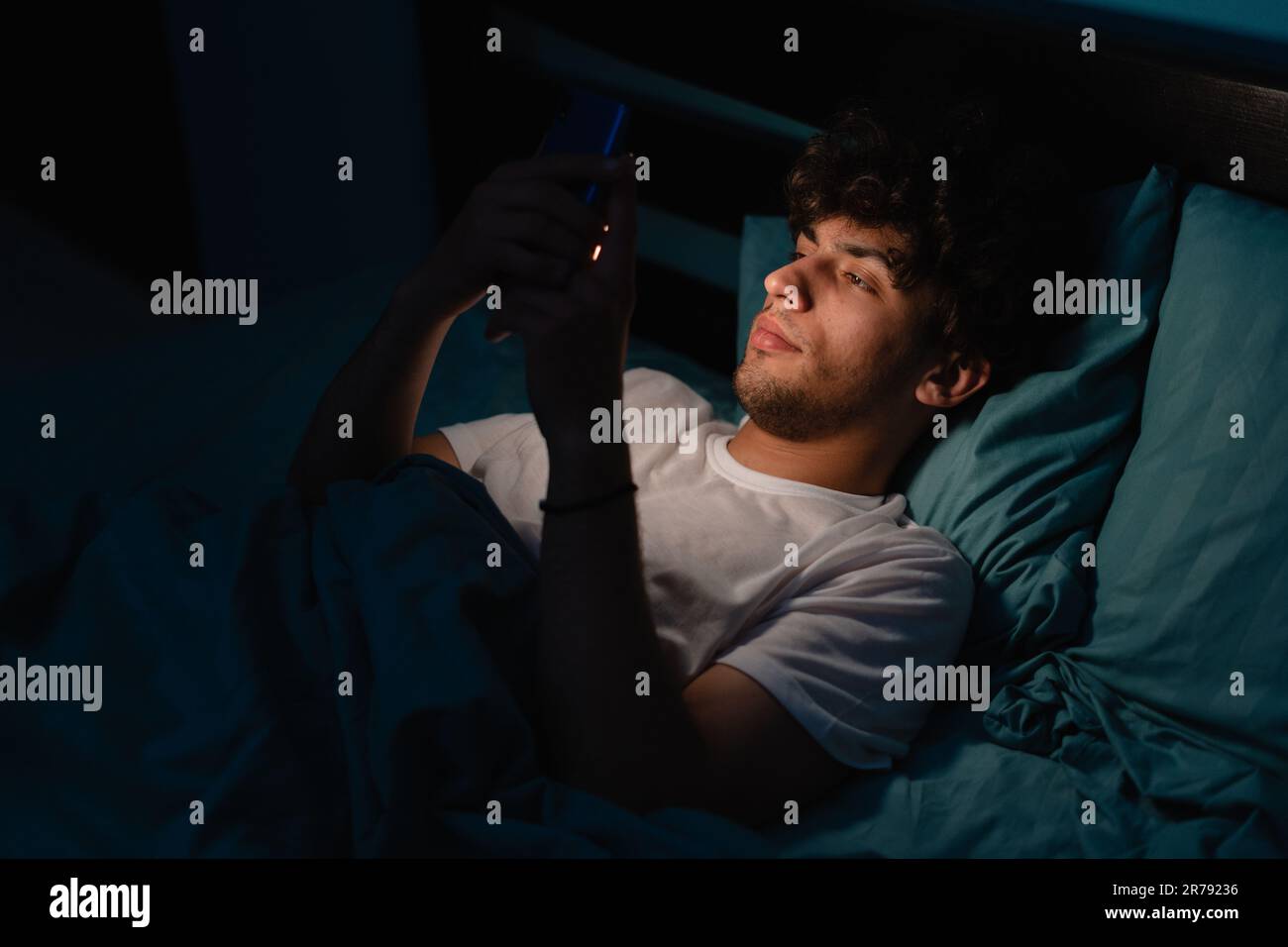 Cell phone addict man awake late at night in bed using smart phone ...