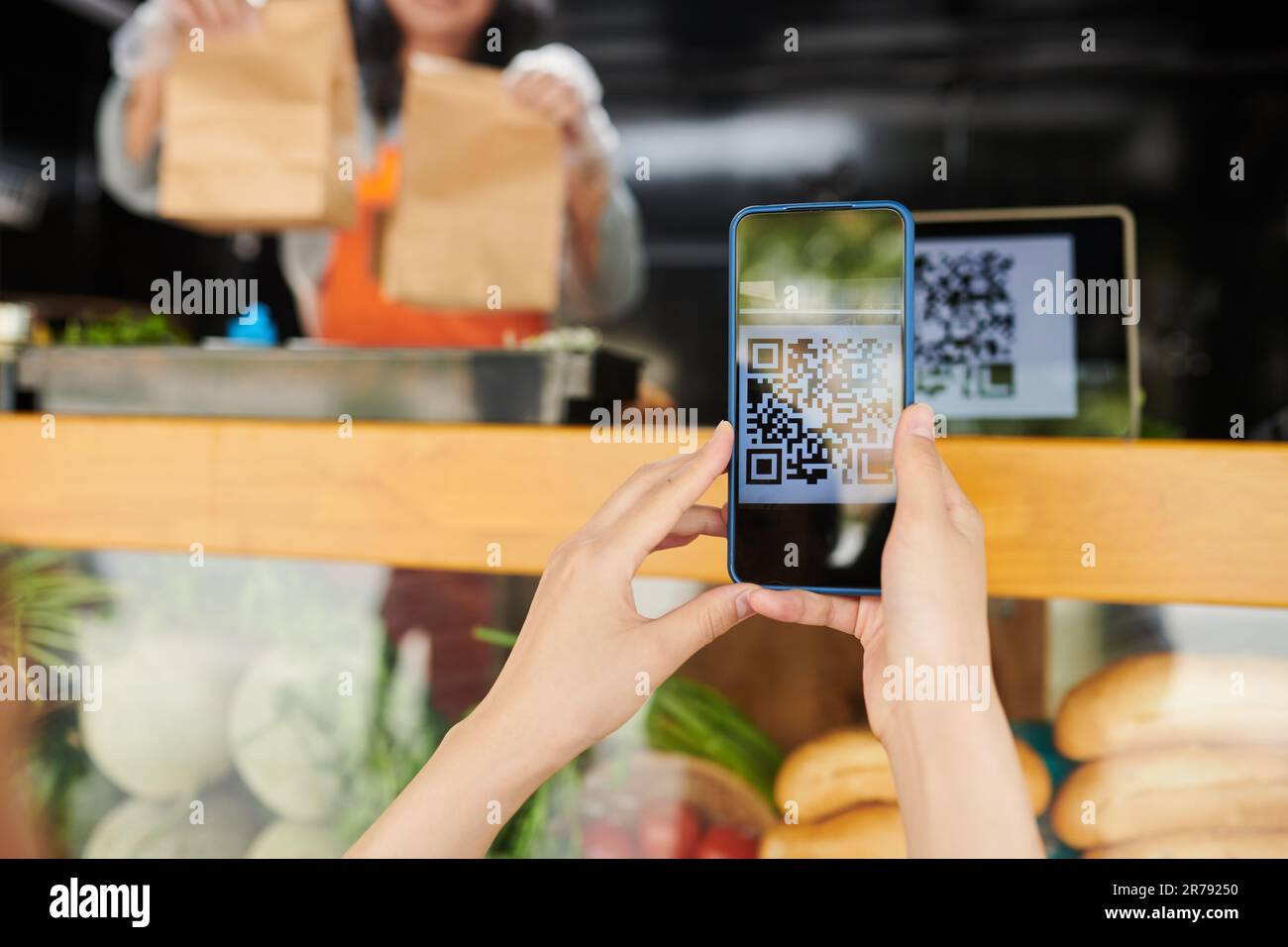 Hands of young female customer scanning qr code of products on ...