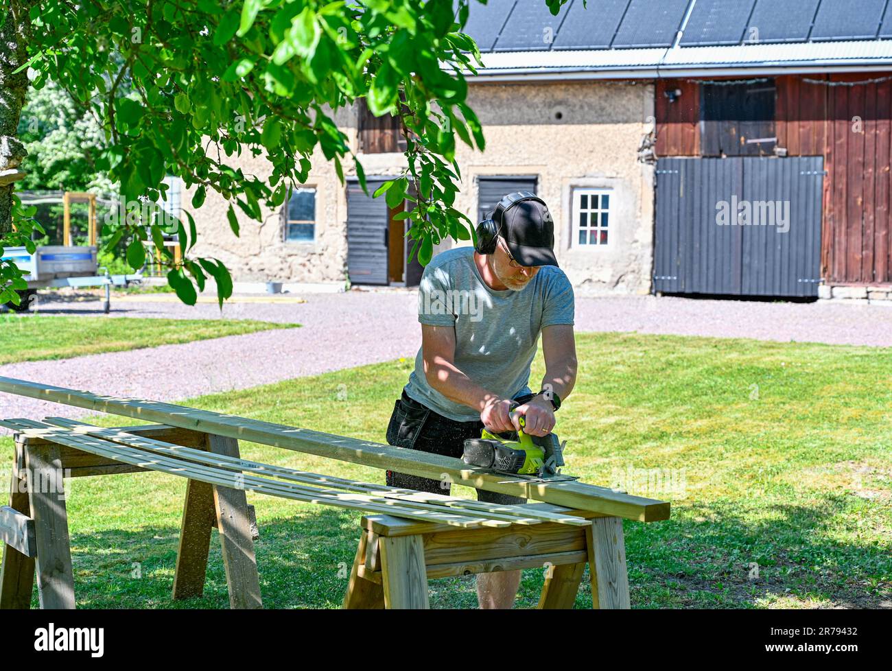 man standing in garden cutting planks with circle saw Stock Photo - Alamy