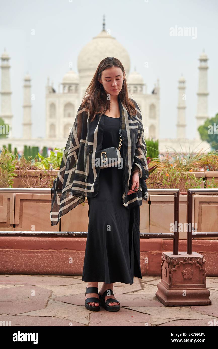 Attractive east asian woman in black dress stay on Taj Mahal background ...