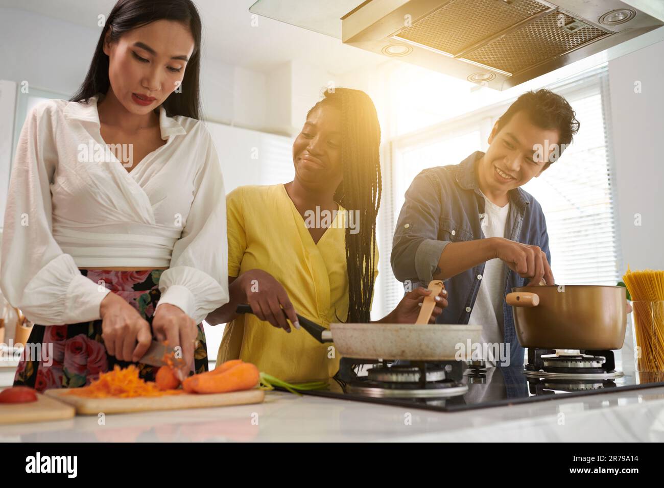 Young black woman standing by gas stove in the kitchen, mixing ...