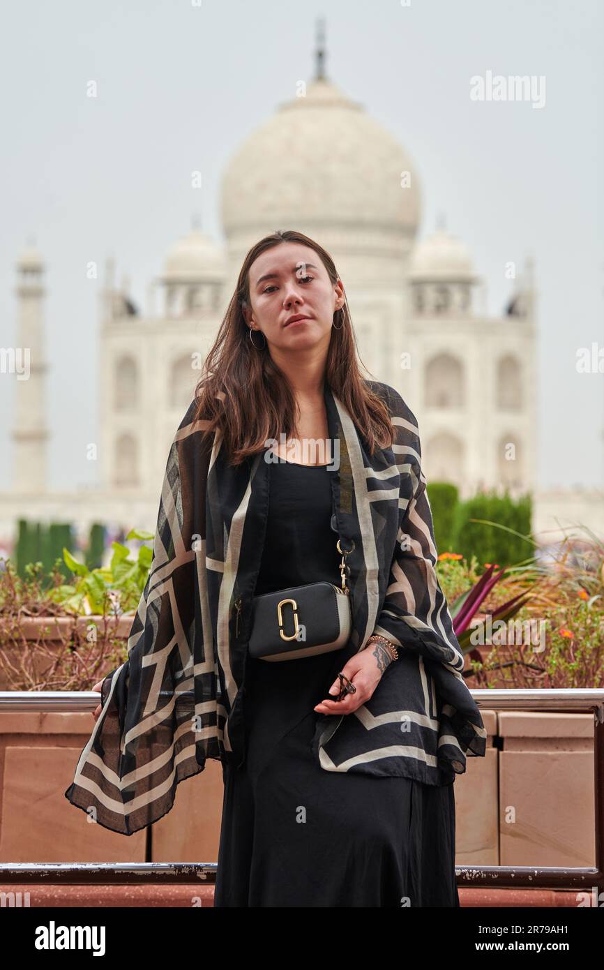 Attractive east asian woman in black dress stay on Taj Mahal background ...