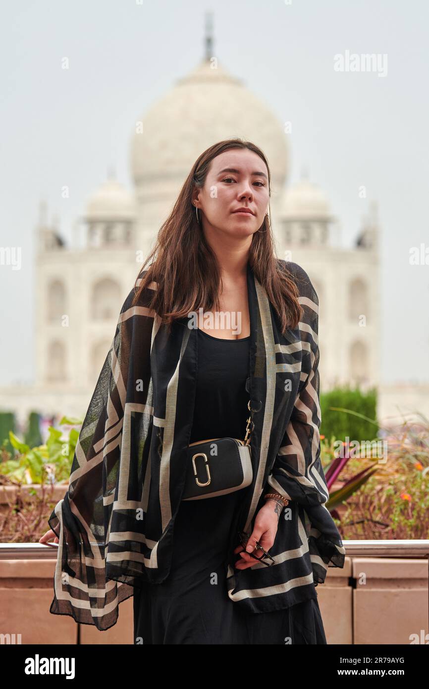 Attractive east asian woman in black dress stay on Taj Mahal background ...