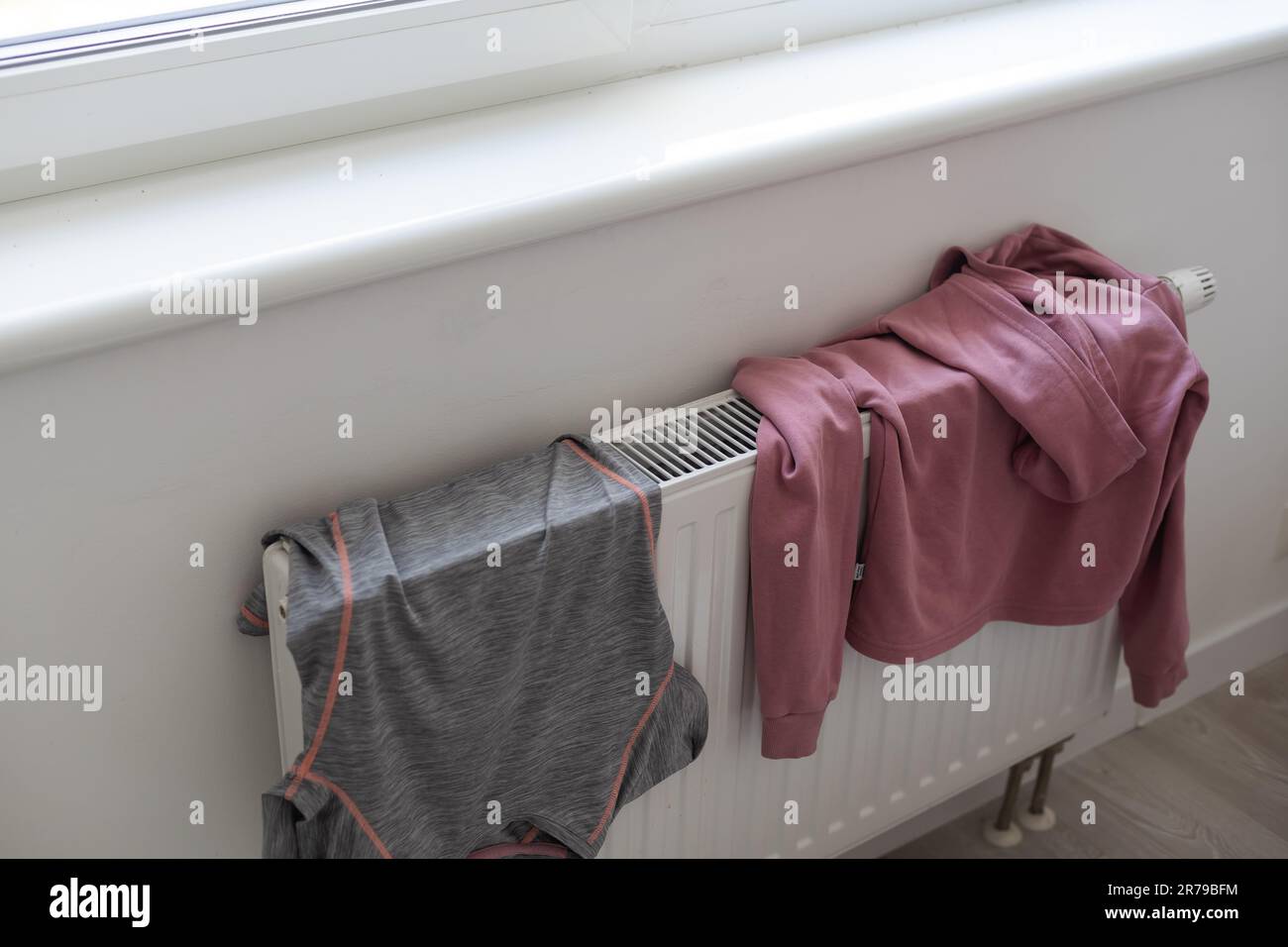 Clothes hanging on white radiator in room Stock Photo - Alamy