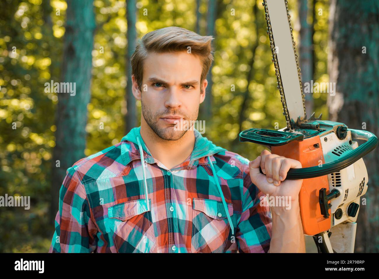Man doing mans job. Lumberjack on serious face carries chainsaw ...