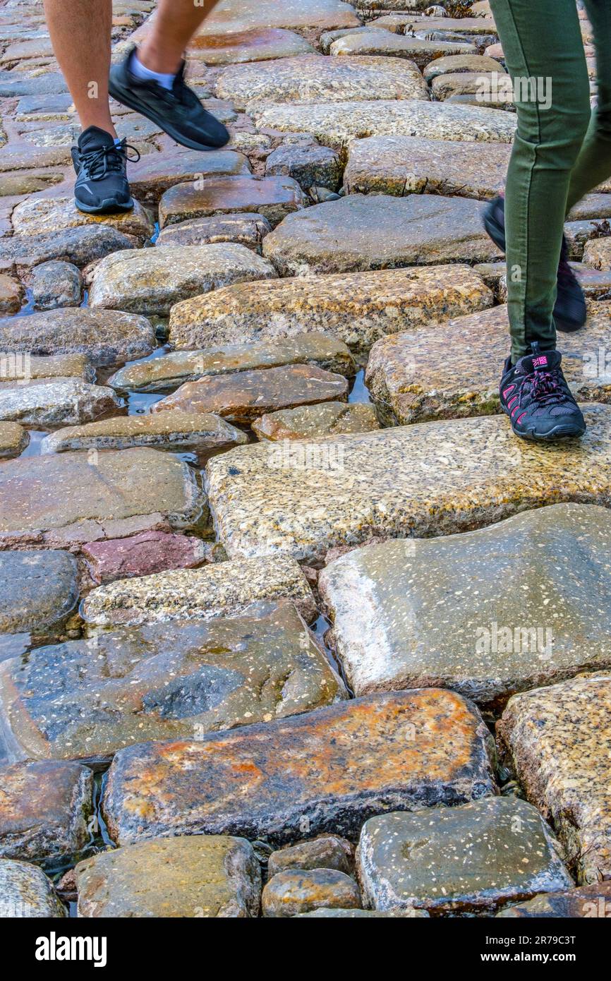 Legs of people walking on the causeway connecting island of St Michael ...