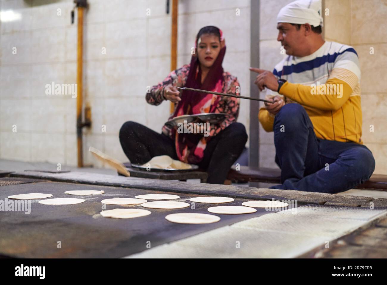 New Delhi, India - 10.11.2022 - Indian volunteers cooking chapati round ...