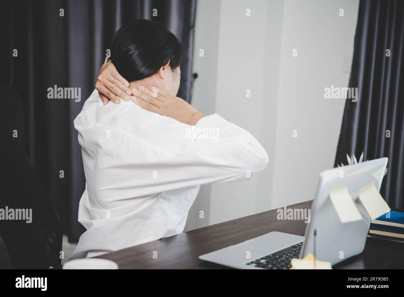 Young asian woman is sitting at work and has tension pain in her neck ...