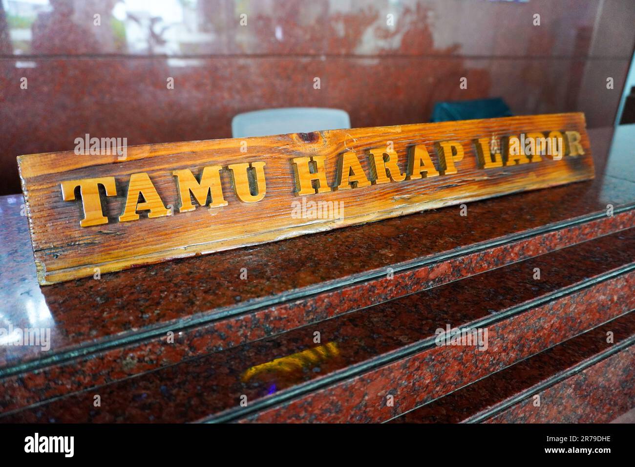 Wooden signboard saying "Tamu Harap Lapor" at the front office in a ...