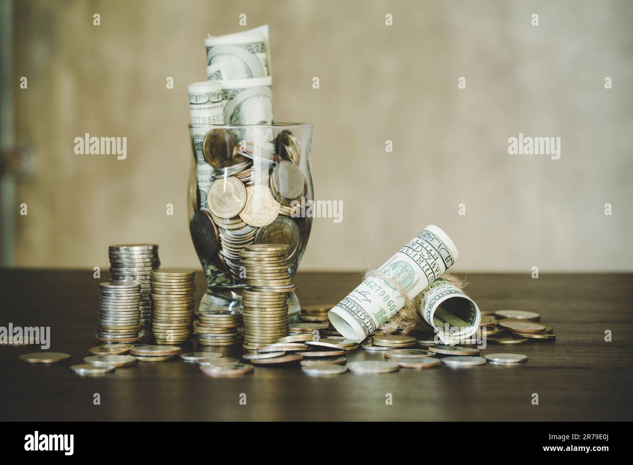 Saving money by dollars with coins in jug glass on dark background ...
