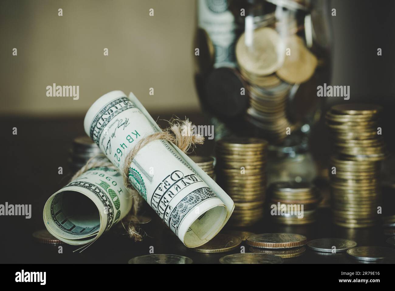 Saving money by dollars with coins in jug glass on dark background ...
