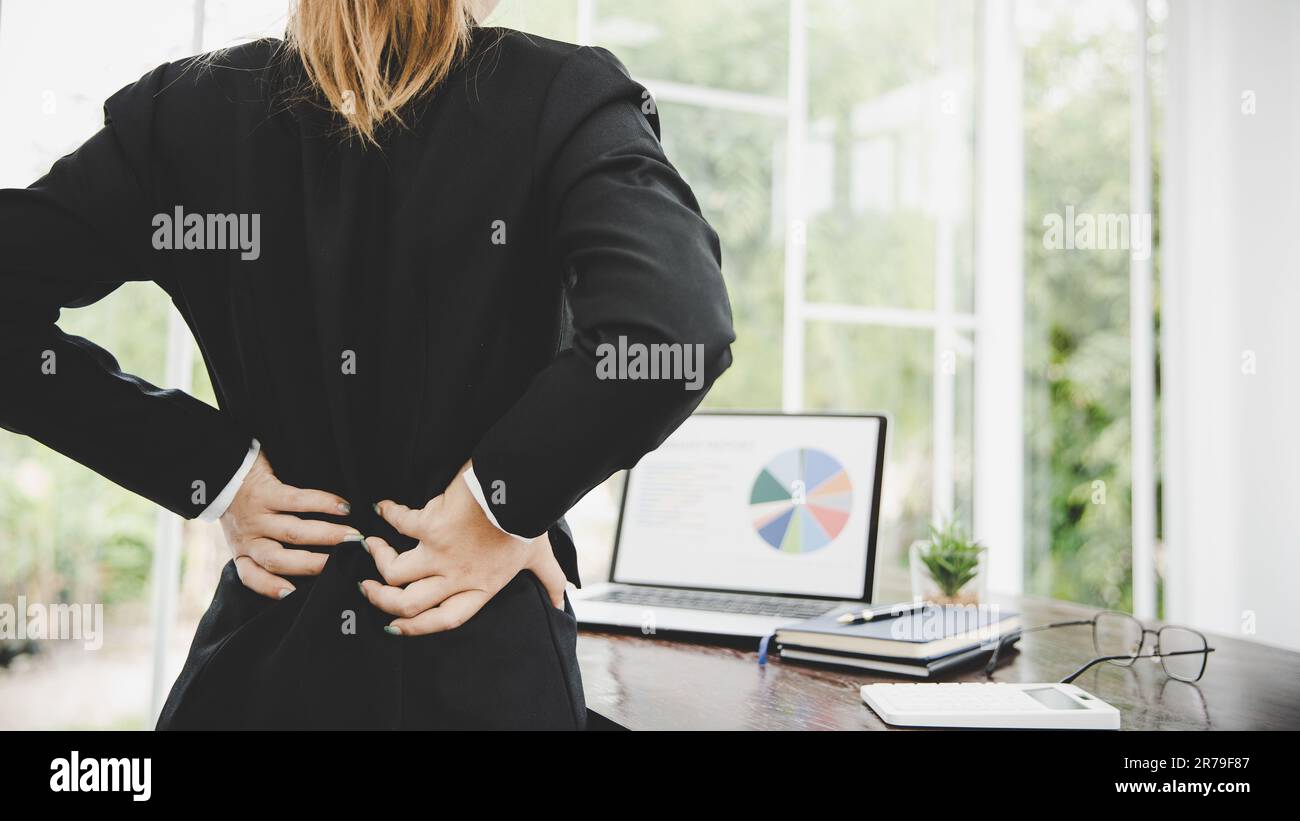 Young business woman at the office with terrible back pain while she is ...