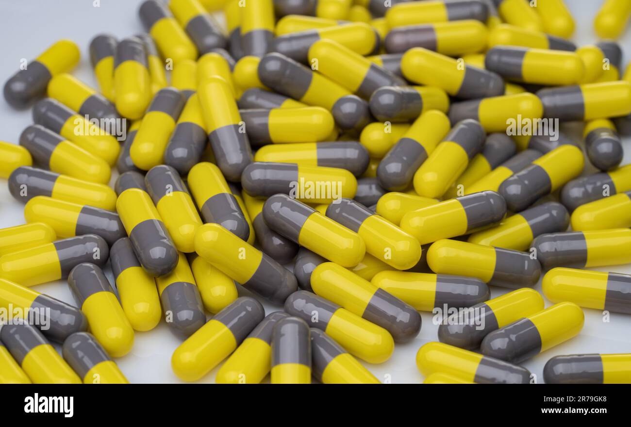 Closeup yellow and gray capsule pills on white background. Prescription ...