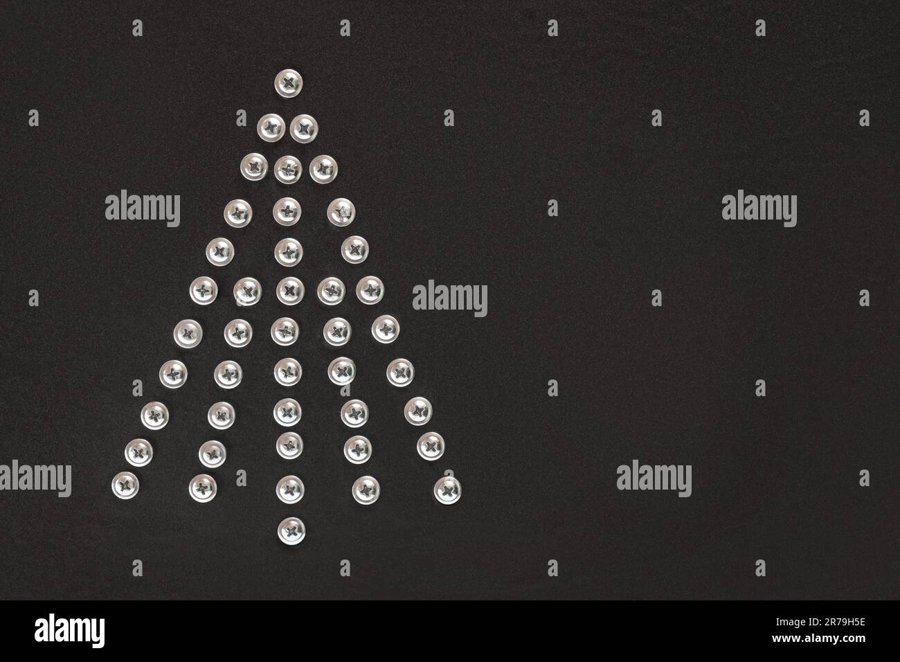 Christmas tree of screws on a black background. Flat lay. Copy space ...