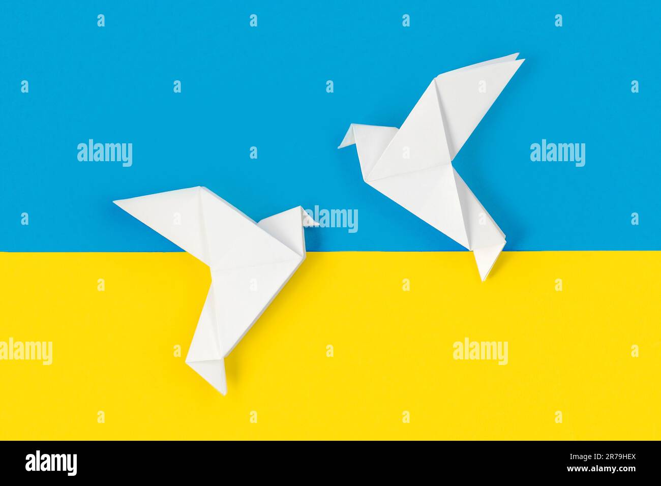 Two white origami paper doves on colors of flag of Ukraine. The concept ...