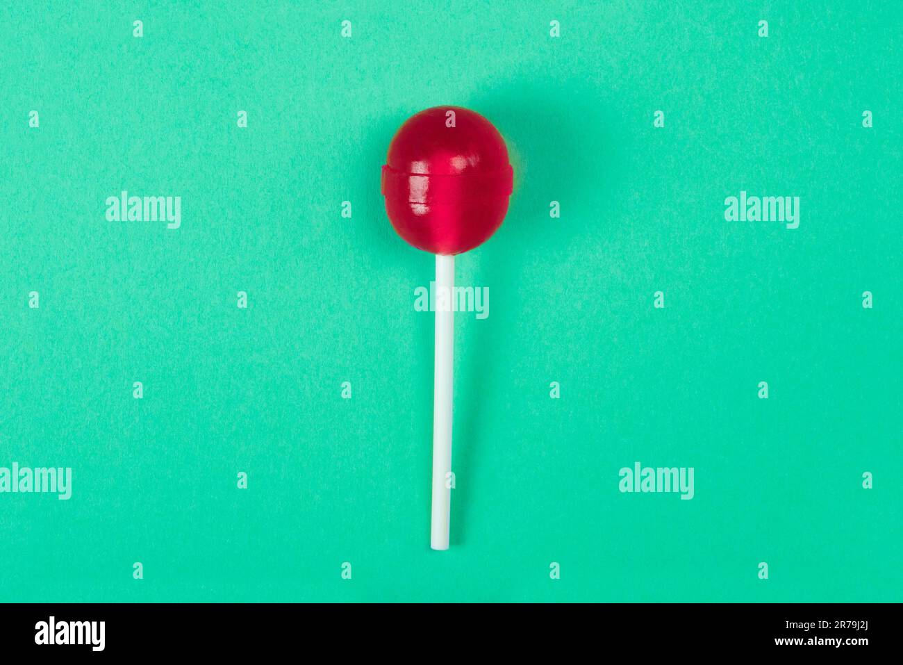 A red lollipop on a stick at the green background, a view from above ...