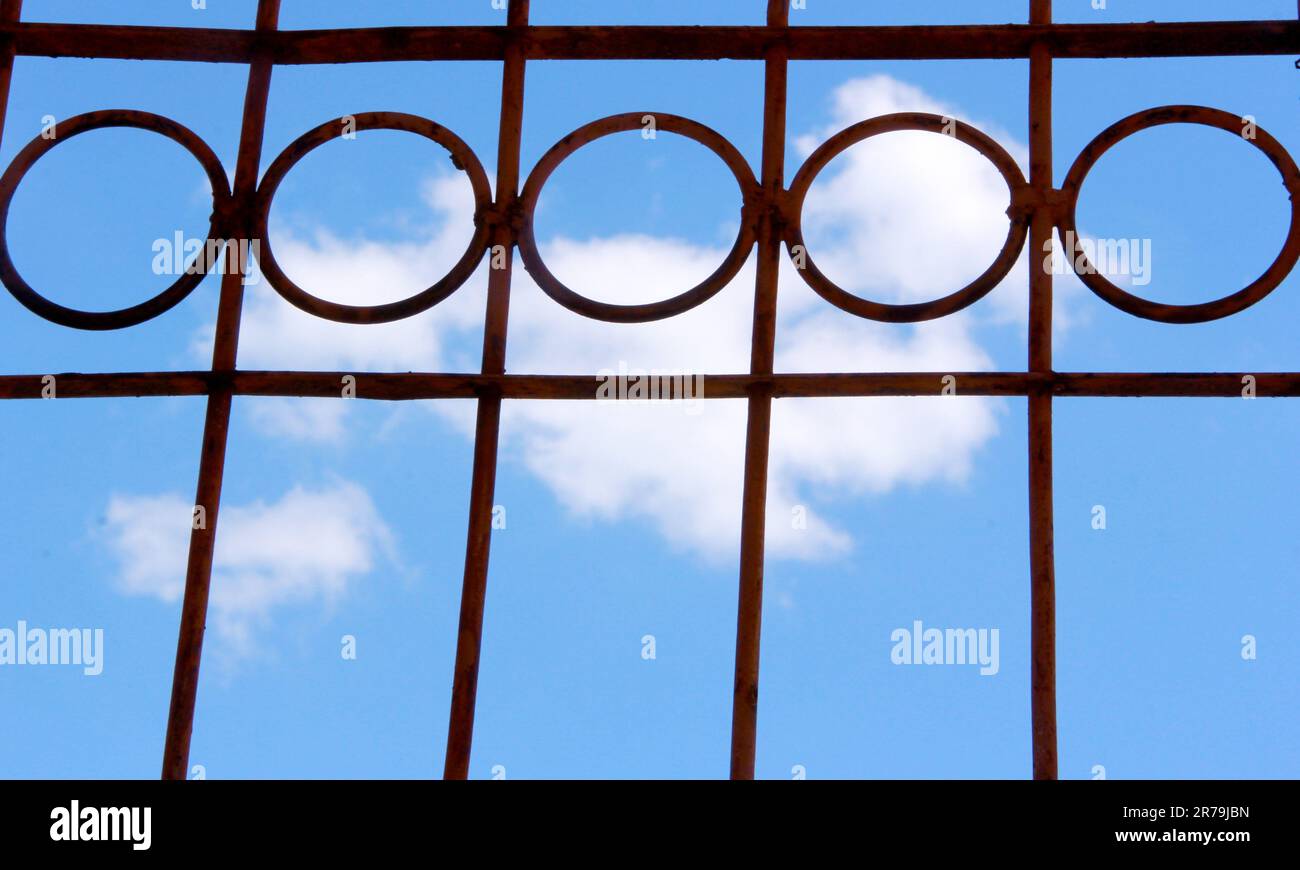 Round steel fence with blue sky and clouds background Stock Photo - Alamy