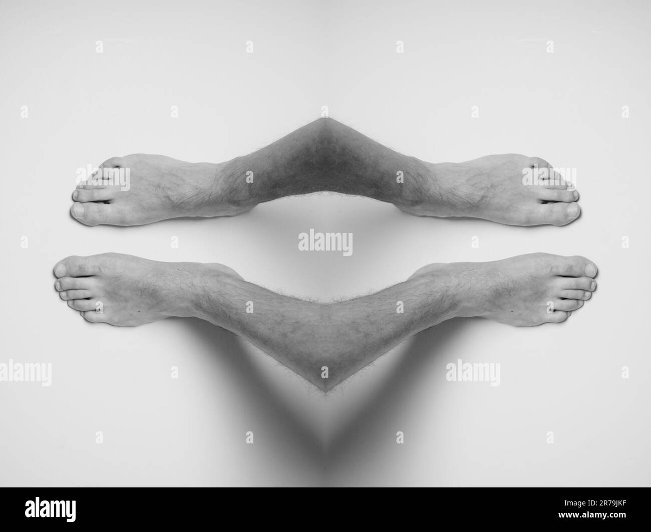 A grayscale of human feet presented in an artistic position crossed in ...