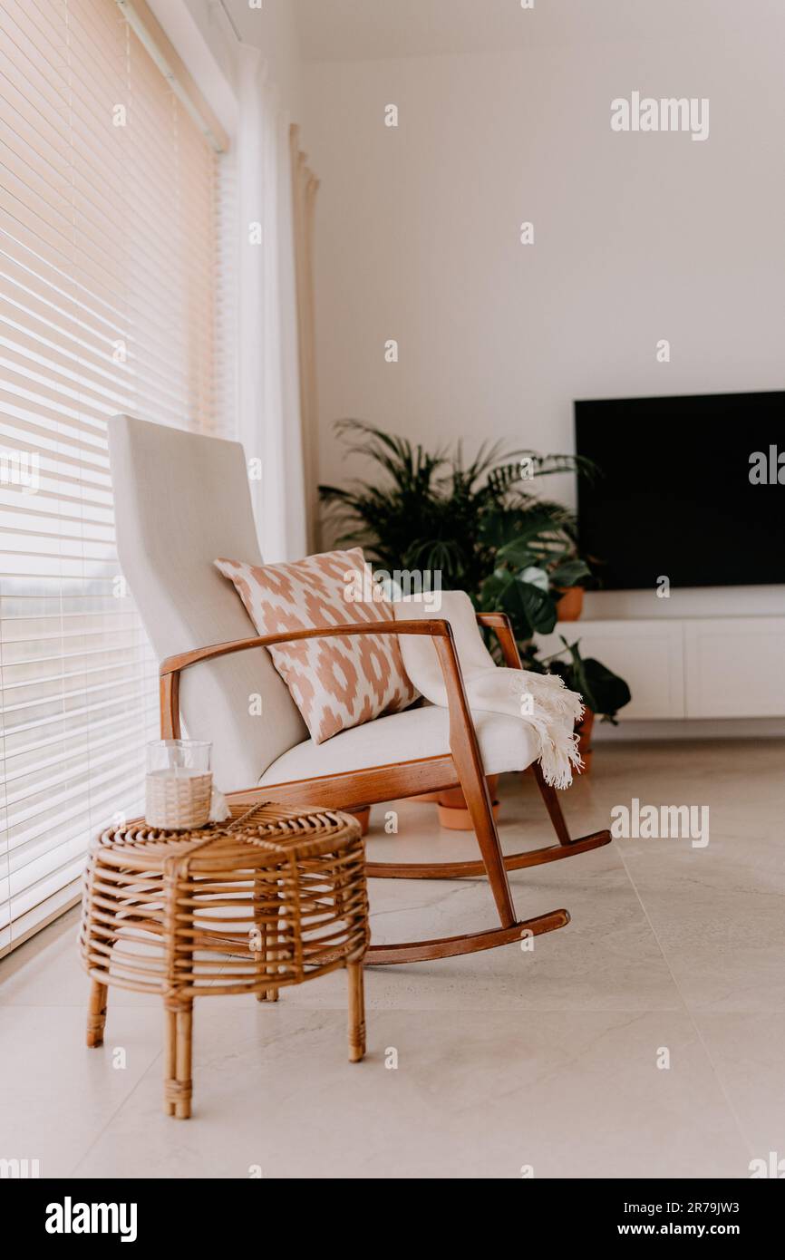 A cozy living room with a comfortable rocking chair, window blinds, and ...