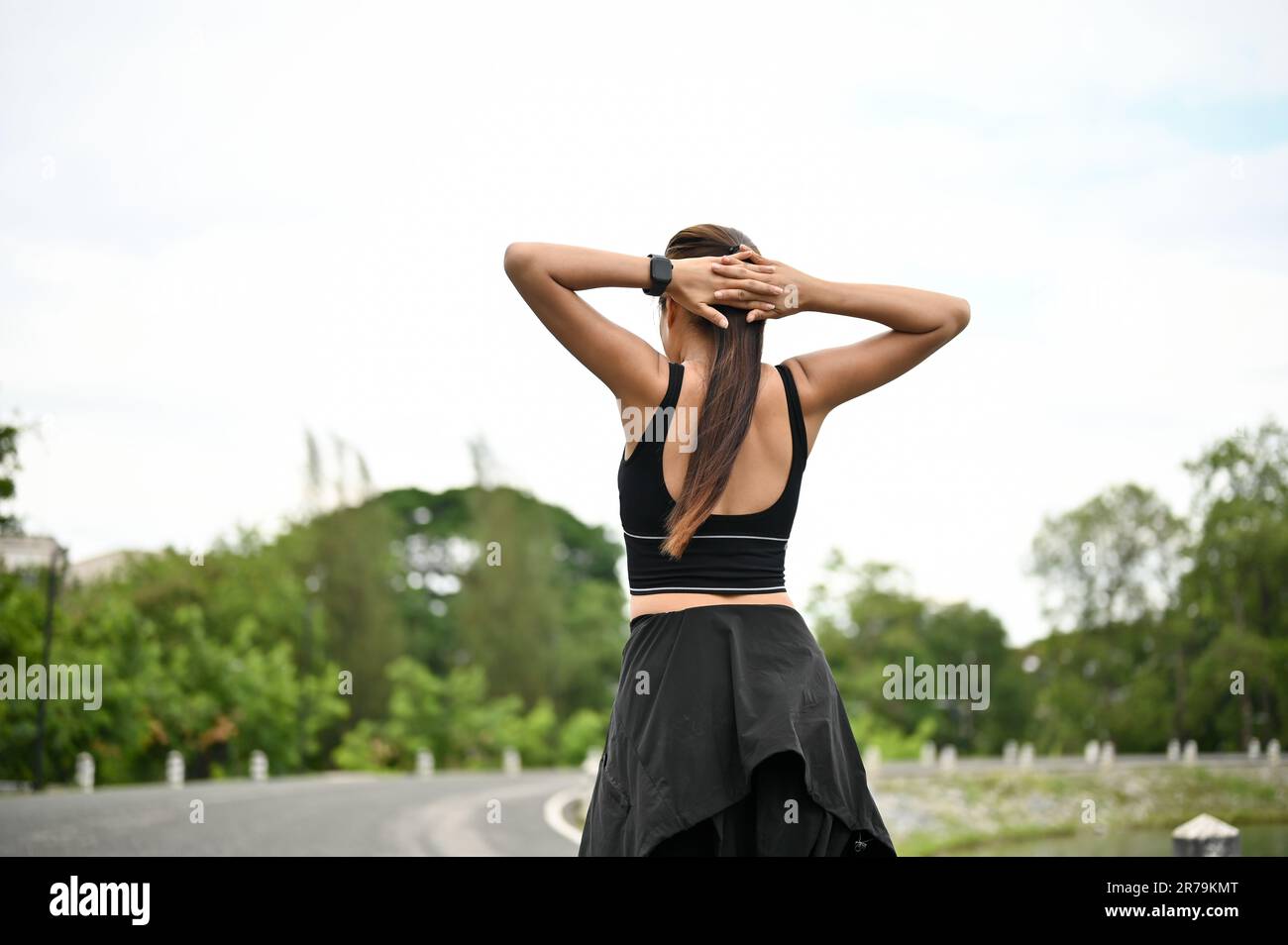 A sporty and tired Asian woman in sportswear is putting her hands ...