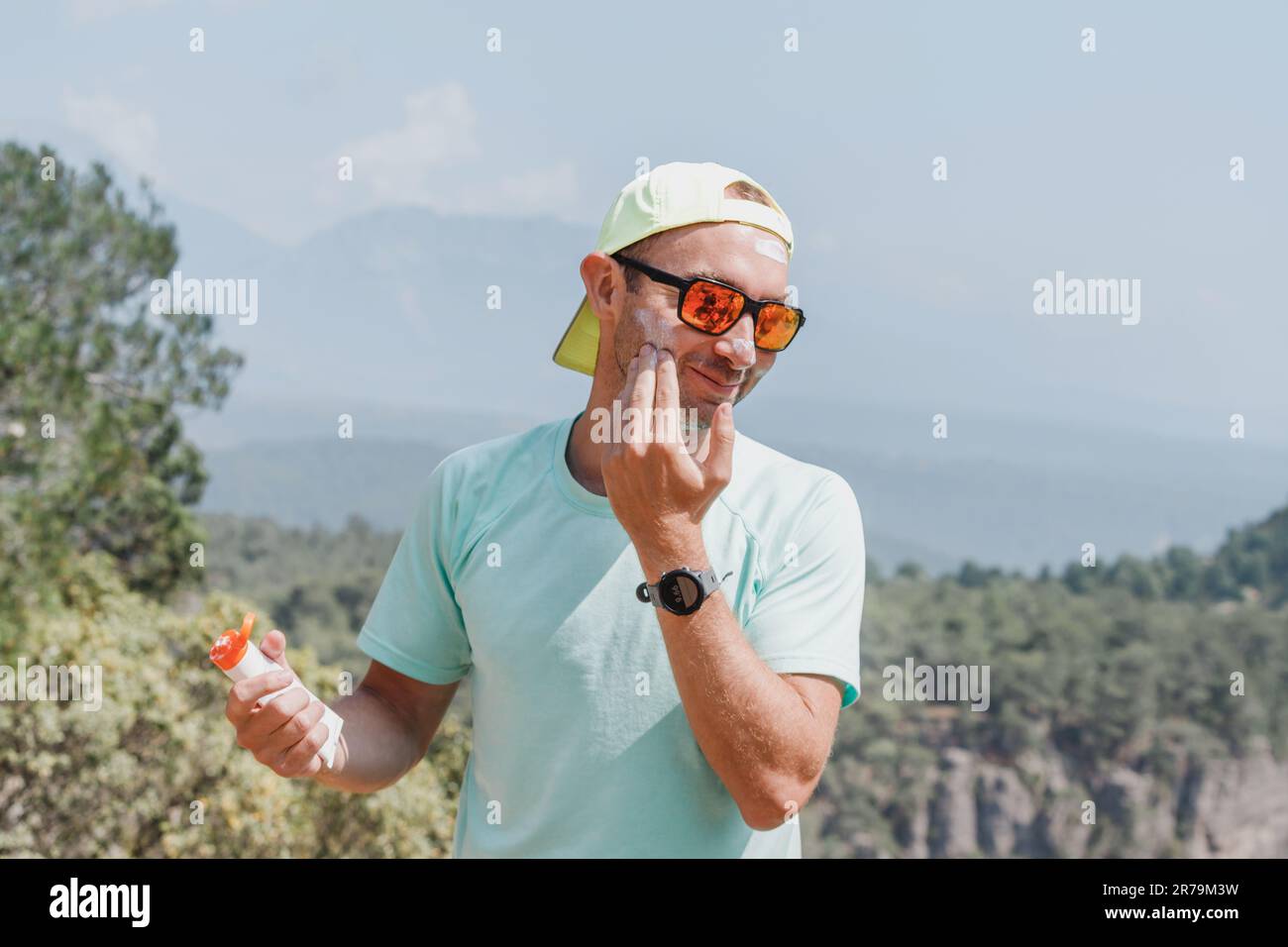 Hiker sporty man sky runner applying sun cream to protect skin from ...