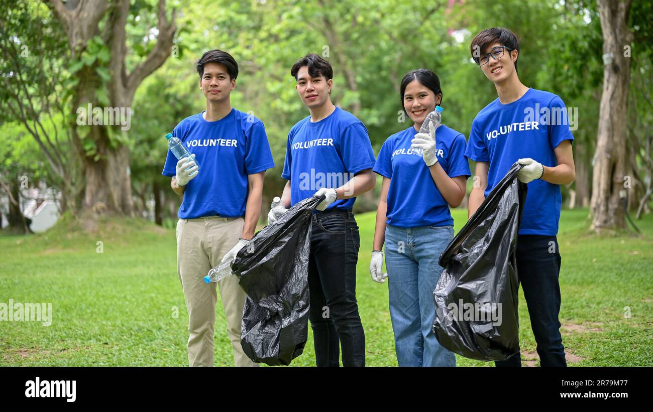 A group of happy young Asian volunteers in uniform stand in a public ...