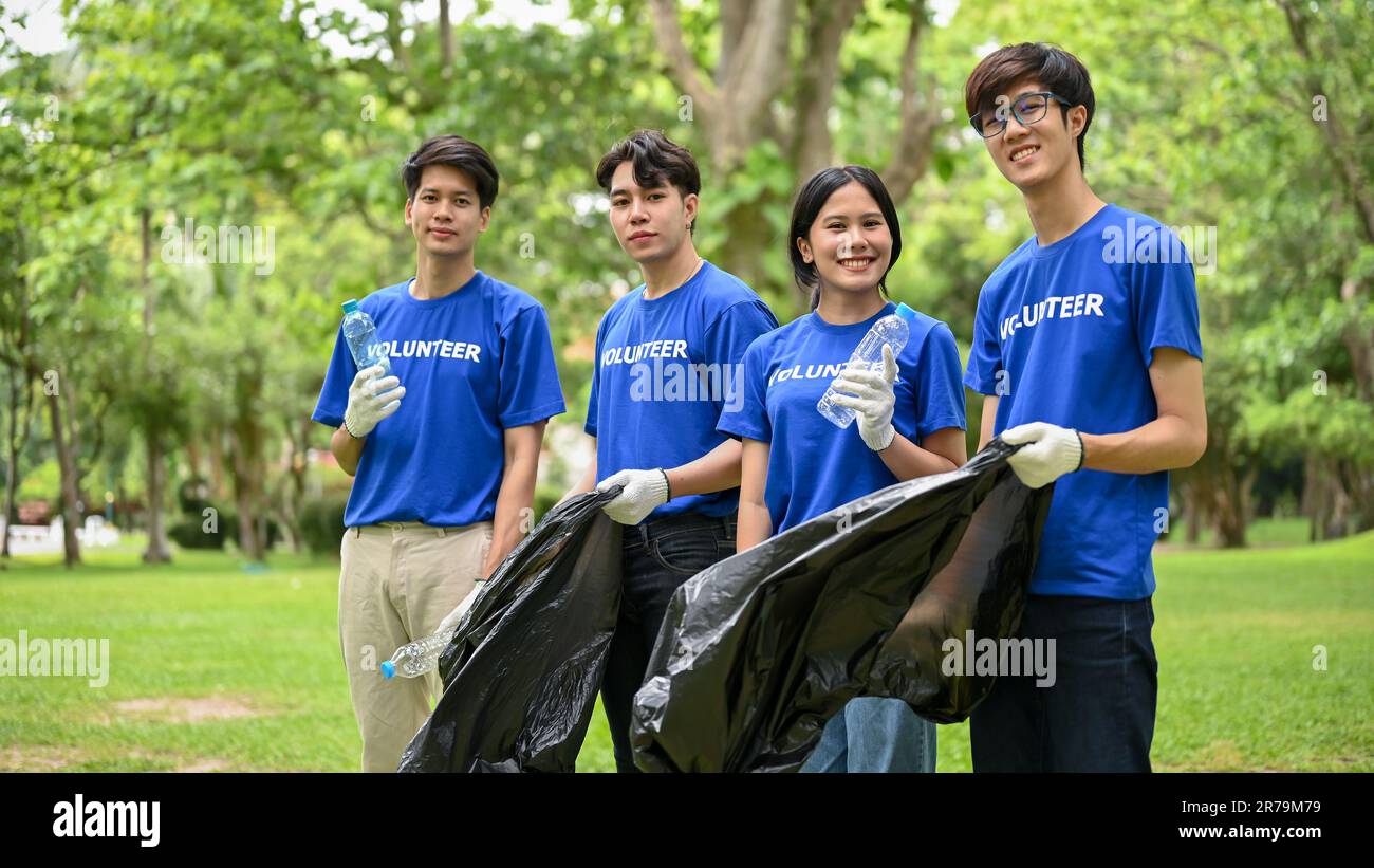 A group of happy young Asian volunteers in uniform stand in a public ...